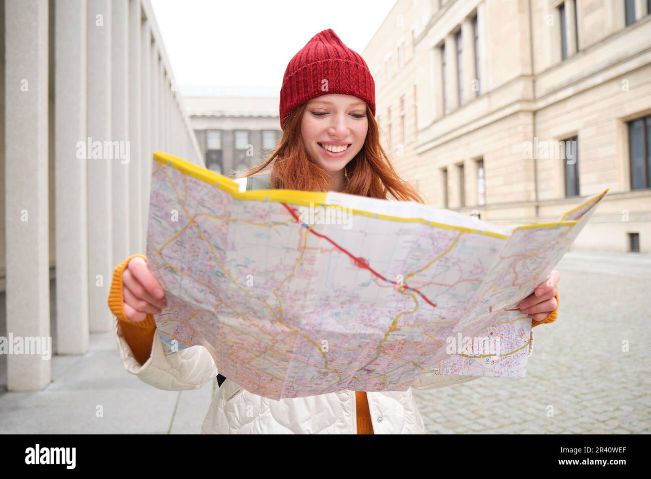 Redhead girl, tourist explores city, looks at paper map to find way for ...
