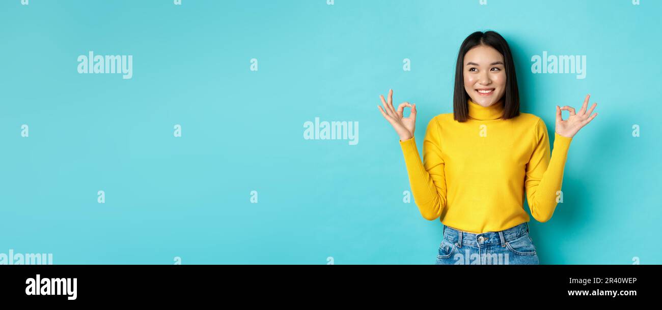 Beautiful japanese girl in yellow sweater, showing Ok signs and smiling ...