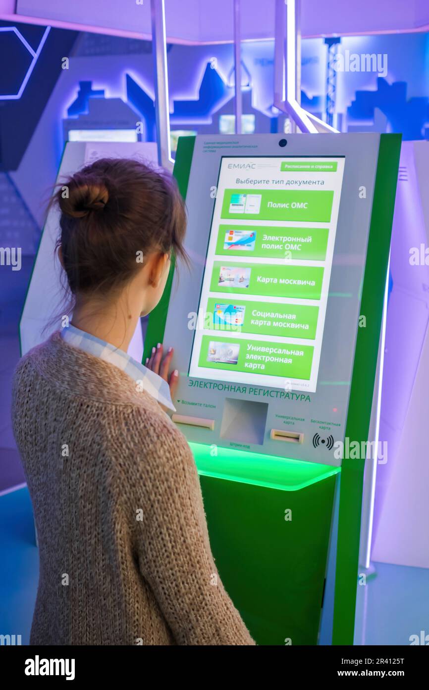 Woman using interactive touchscreen green kiosk at modern museum or ...