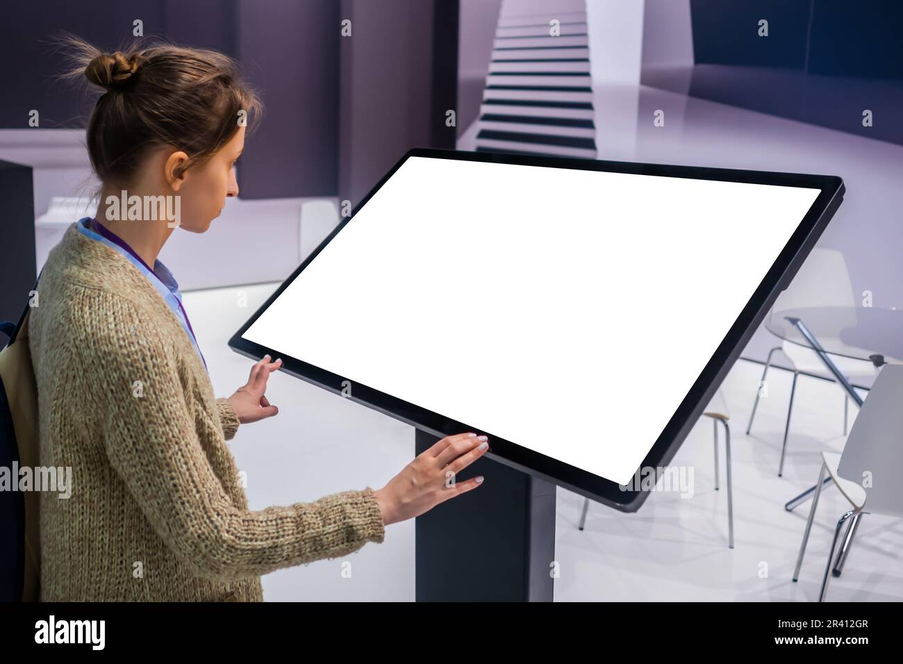 Woman using interactive empty white touchscreen display kiosk at ...