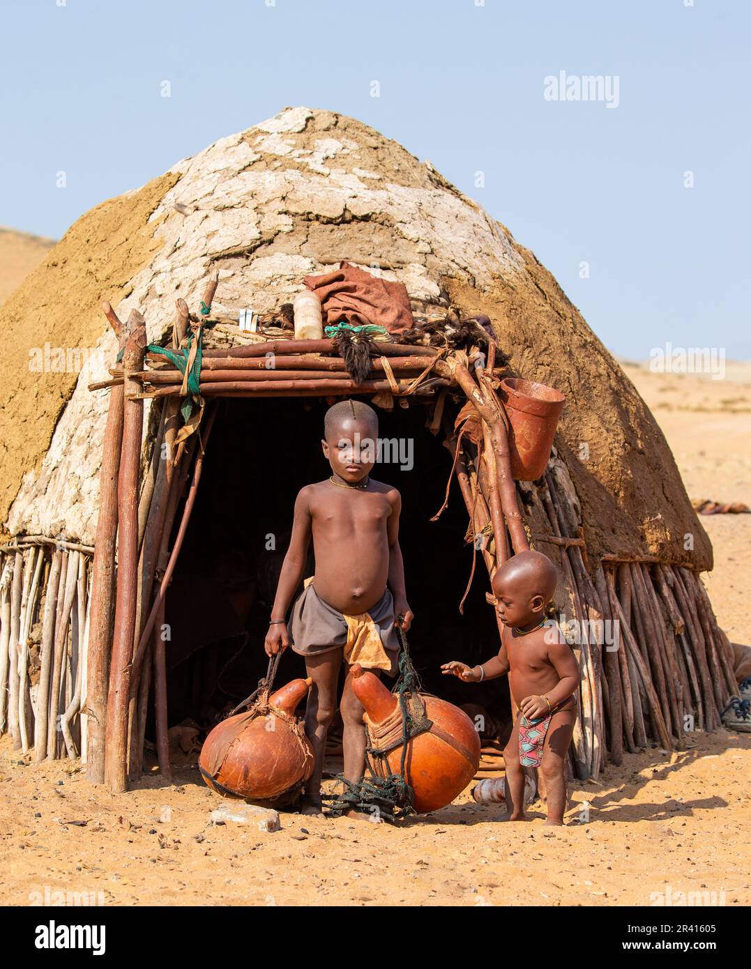Children of the Himba tribe are standing outside their house with ...