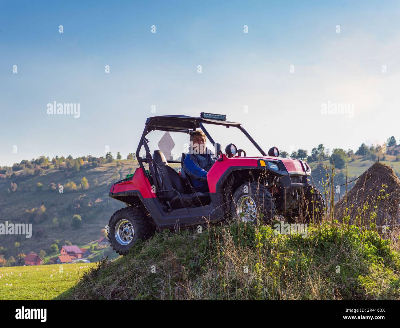 A man driving a quad ATV motorcycle through beautiful meadow landscapes ...