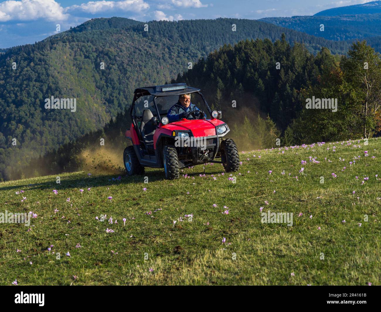 A man driving a quad ATV motorcycle through beautiful meadow landscapes Stock Photo - Alamy