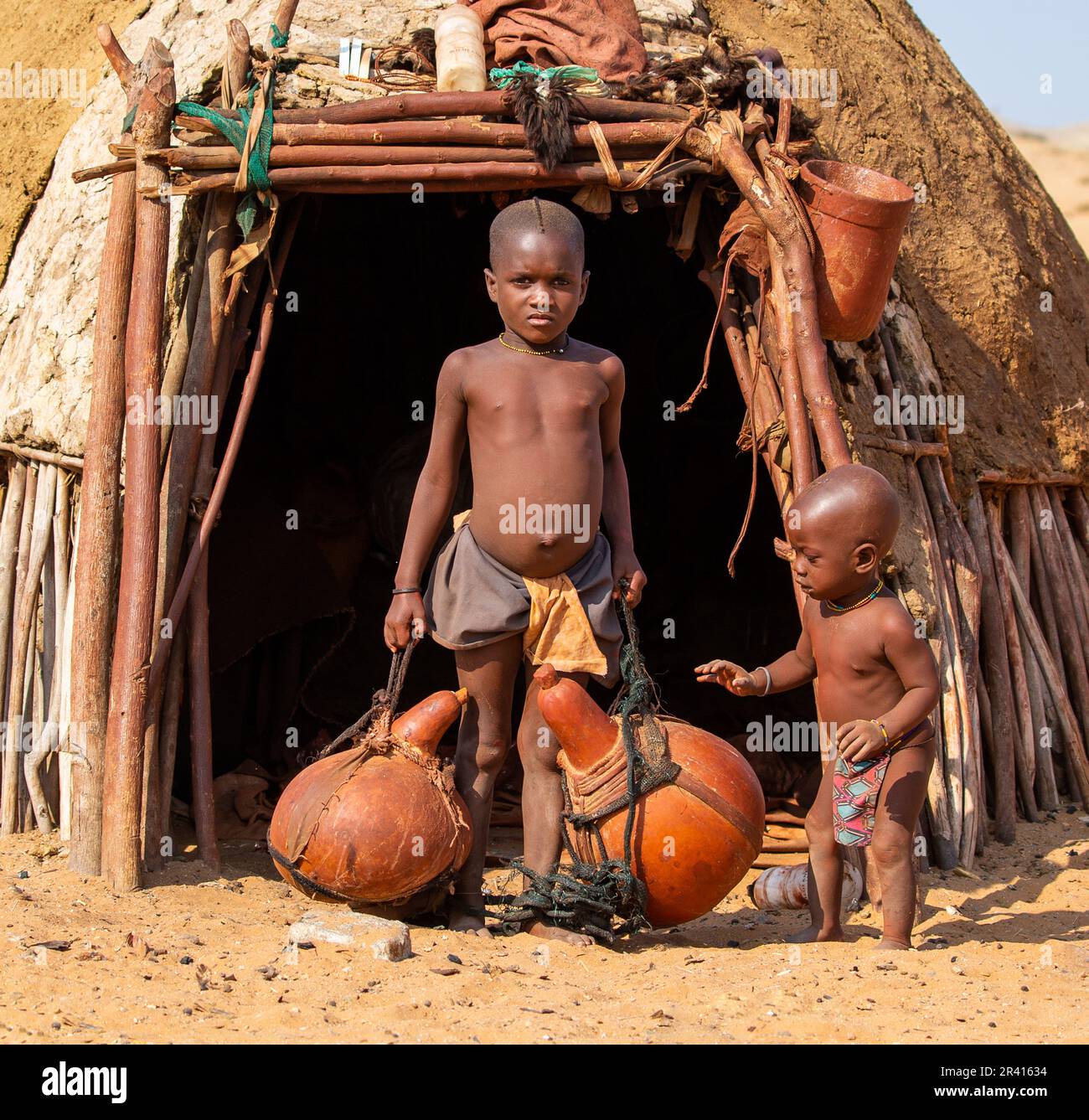 Children of the Himba tribe are standing outside their house with ...