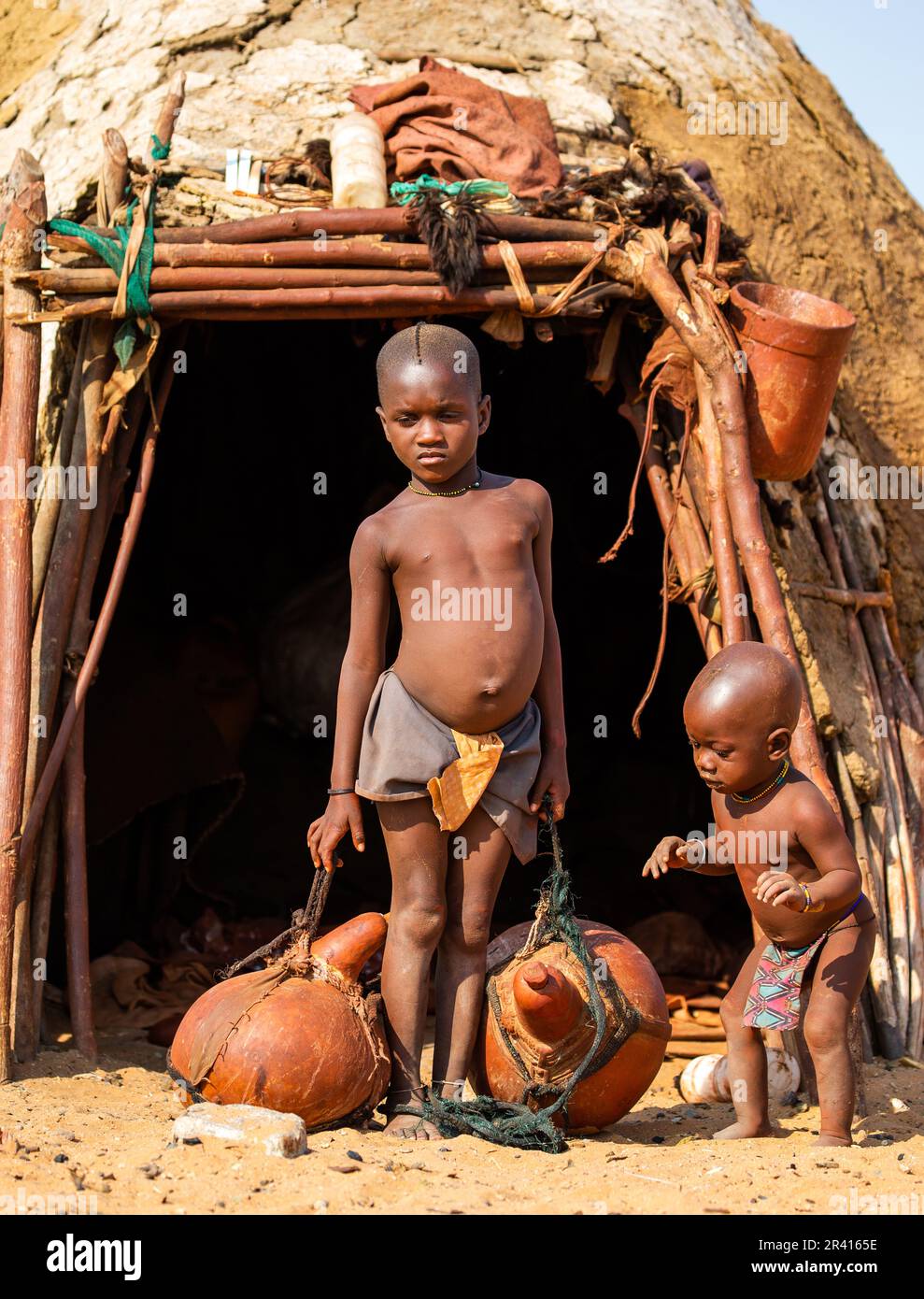 Children of the Himba tribe are standing outside their house with ...