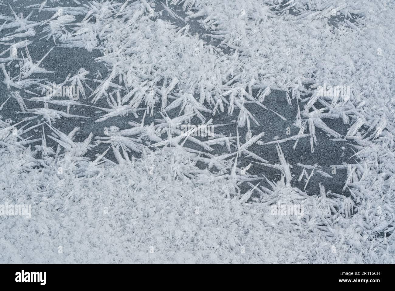 Ice crystals forming spike shapes on frozen river, closeup macro detail ...