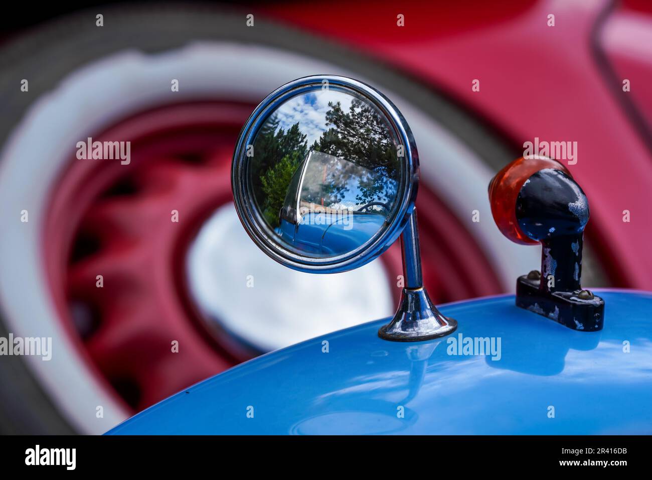 Rear mirror mounted on front fender of blue color vintage car, closeup ...