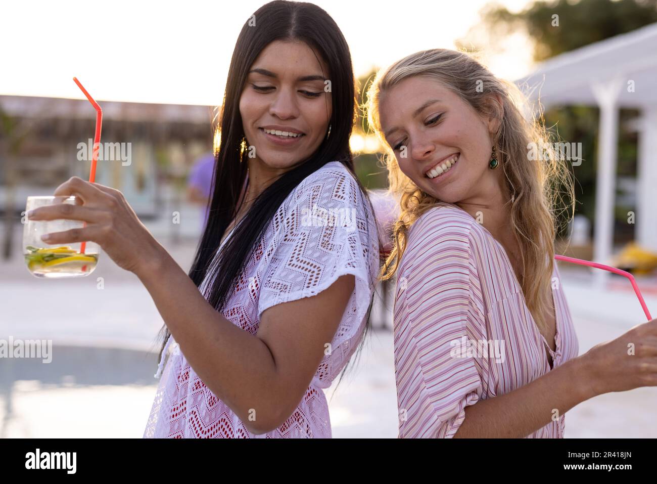 Happy diverse female friends having party by swimming pool, holding ...