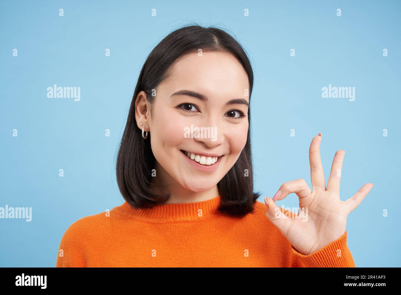 Close up portrait of smiling beautiful asian woman, shows okay, ok ...