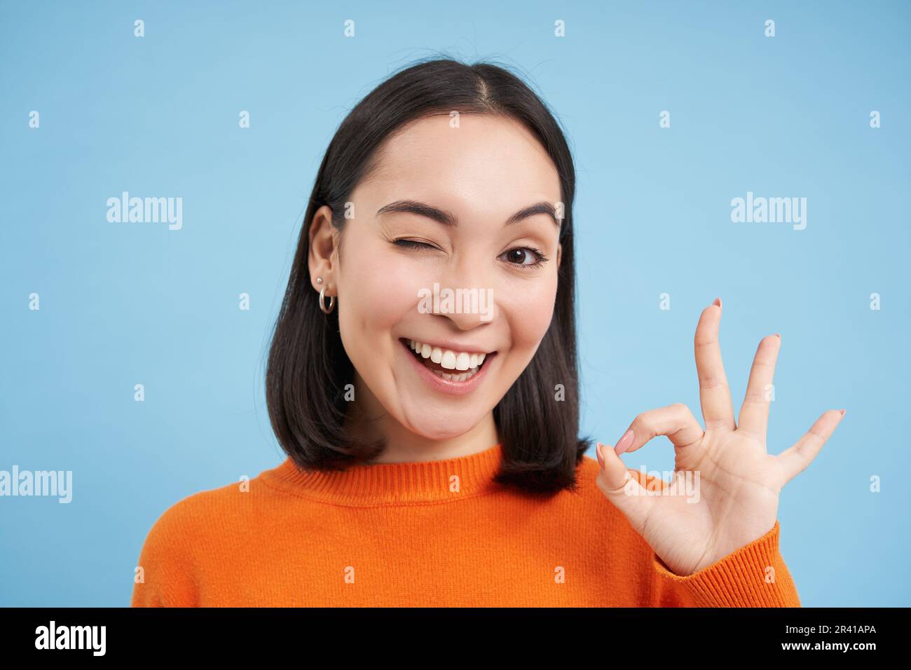 Close up portrait of smiling beautiful asian woman, shows okay, ok ...
