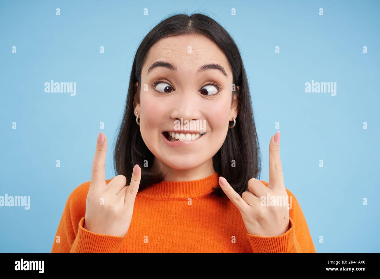 Close up of happy korean woman, shows rock n roll, heavy metal gesture ...