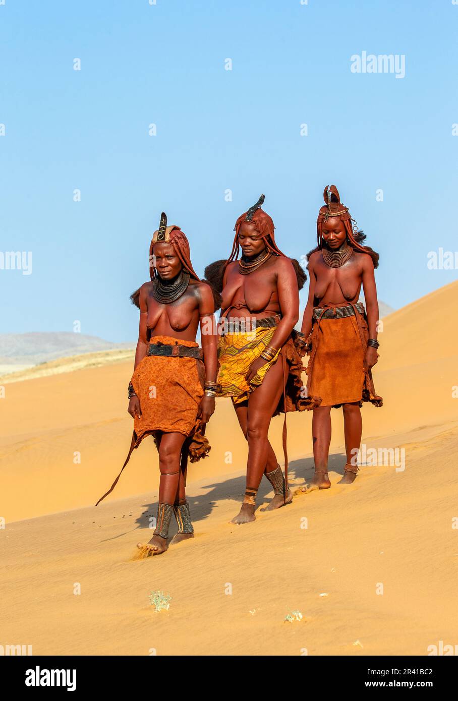 Three women of the Himba tribe in traditional dress walk in the desert Stock Photo - Alamy