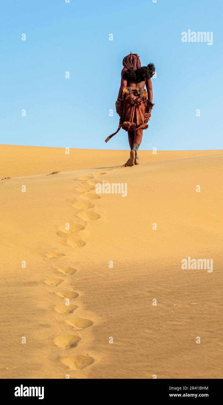 Lone figure of a Himba woman walks across the sand dunes Stock Photo ...
