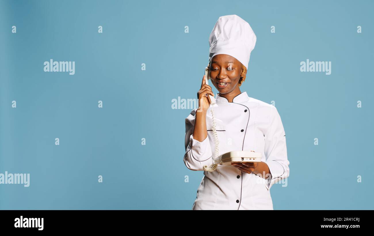 Young gourmet chef using retro landline phone to call Stock Photo - Alamy