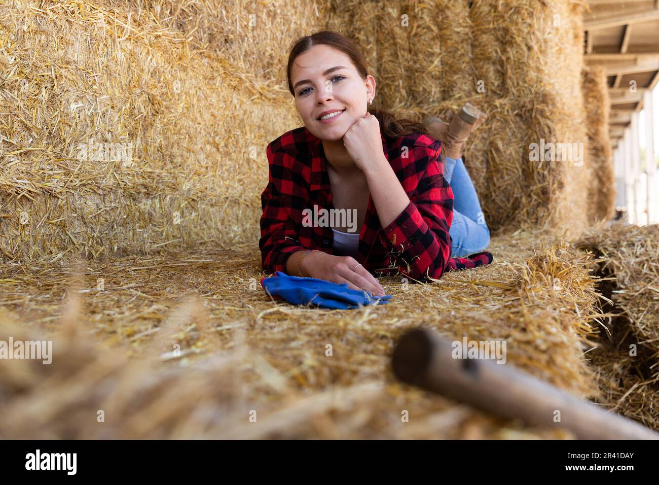 Cheerful young woman farm worker lying on hayloft Stock Photo - Alamy