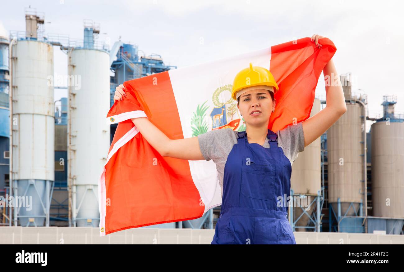 Upset disappointed young female engineer in helmet waving state flag of ...