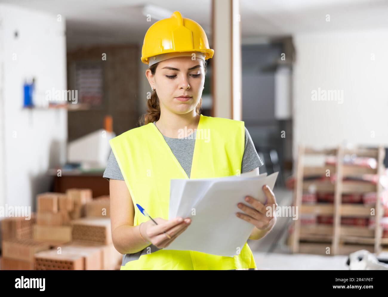 Female civil engineer making notes while controlling construction site ...