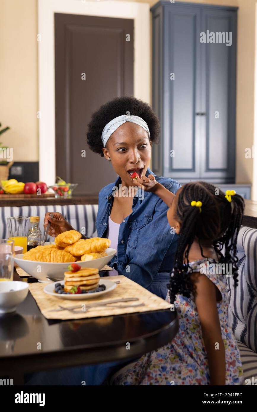 African american girl feeding strawberry to mother while having ...