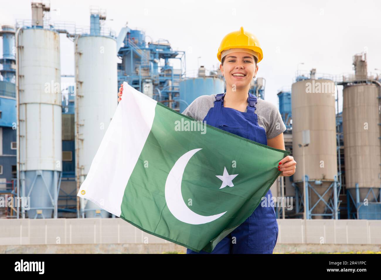 Young female engineer in helmet waving state flag of Pakistan while ...
