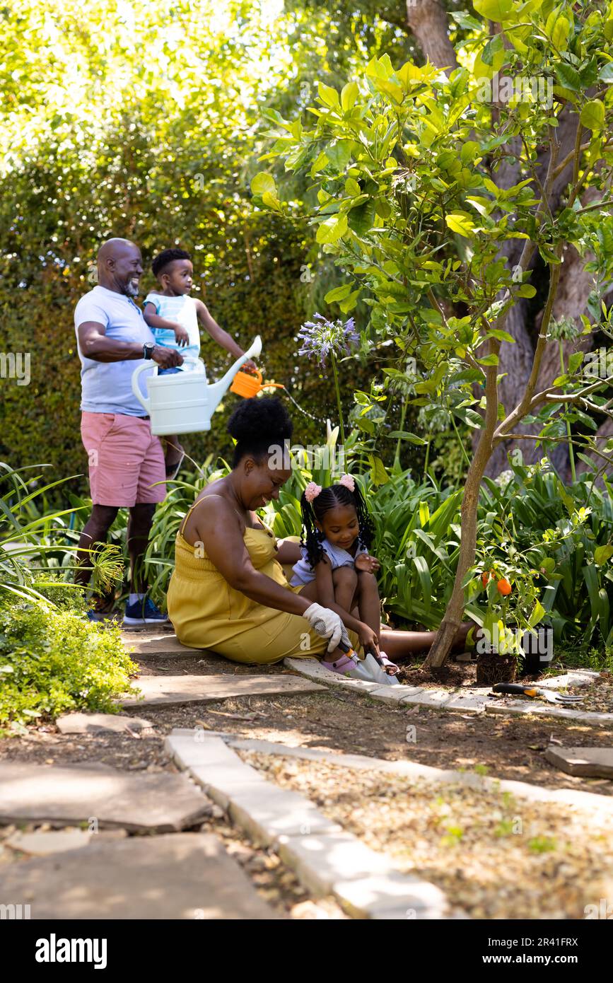 African american man and grandson watering plants while grandmother and ... African american man and grandson watering plants while grandmother and ...