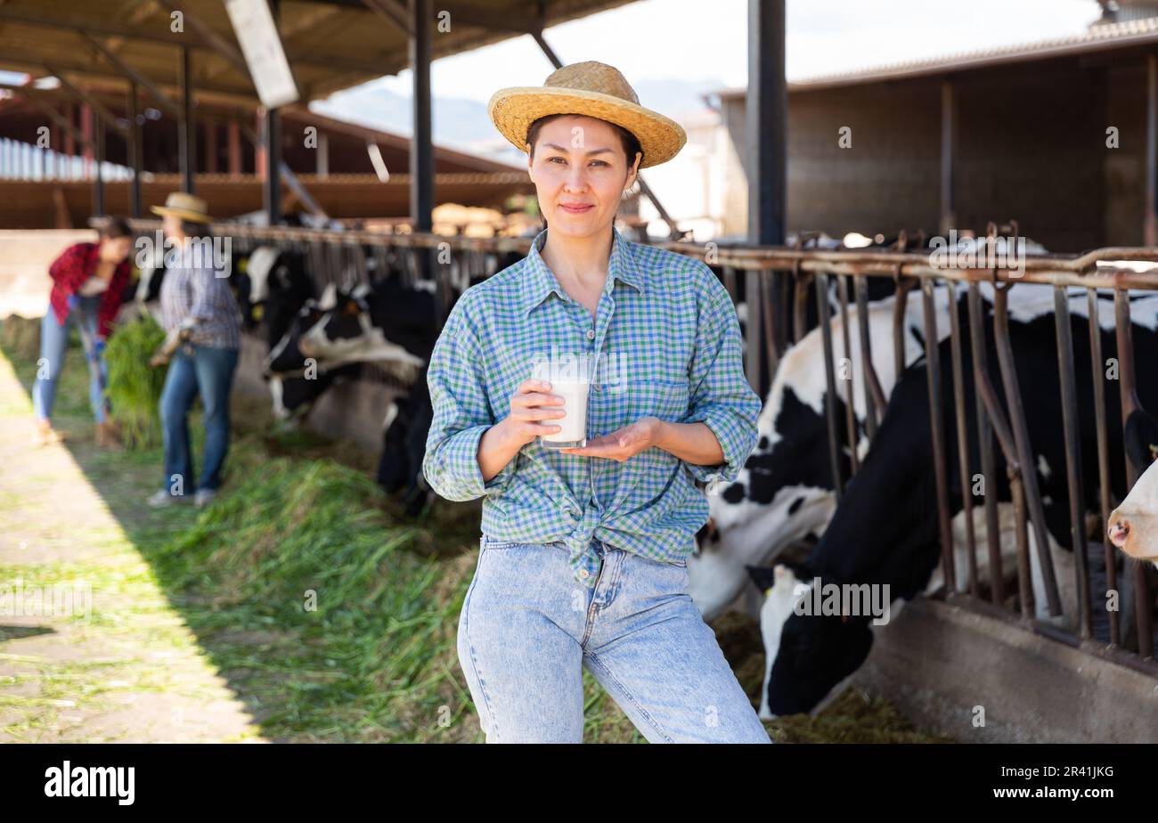 Asian woman dairy farm owner with glass of milk in cowshed Stock Photo ...