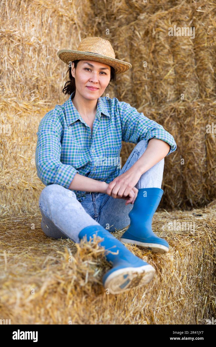 Female farmer posing in the barn against backdrop of hay bales Stock ...