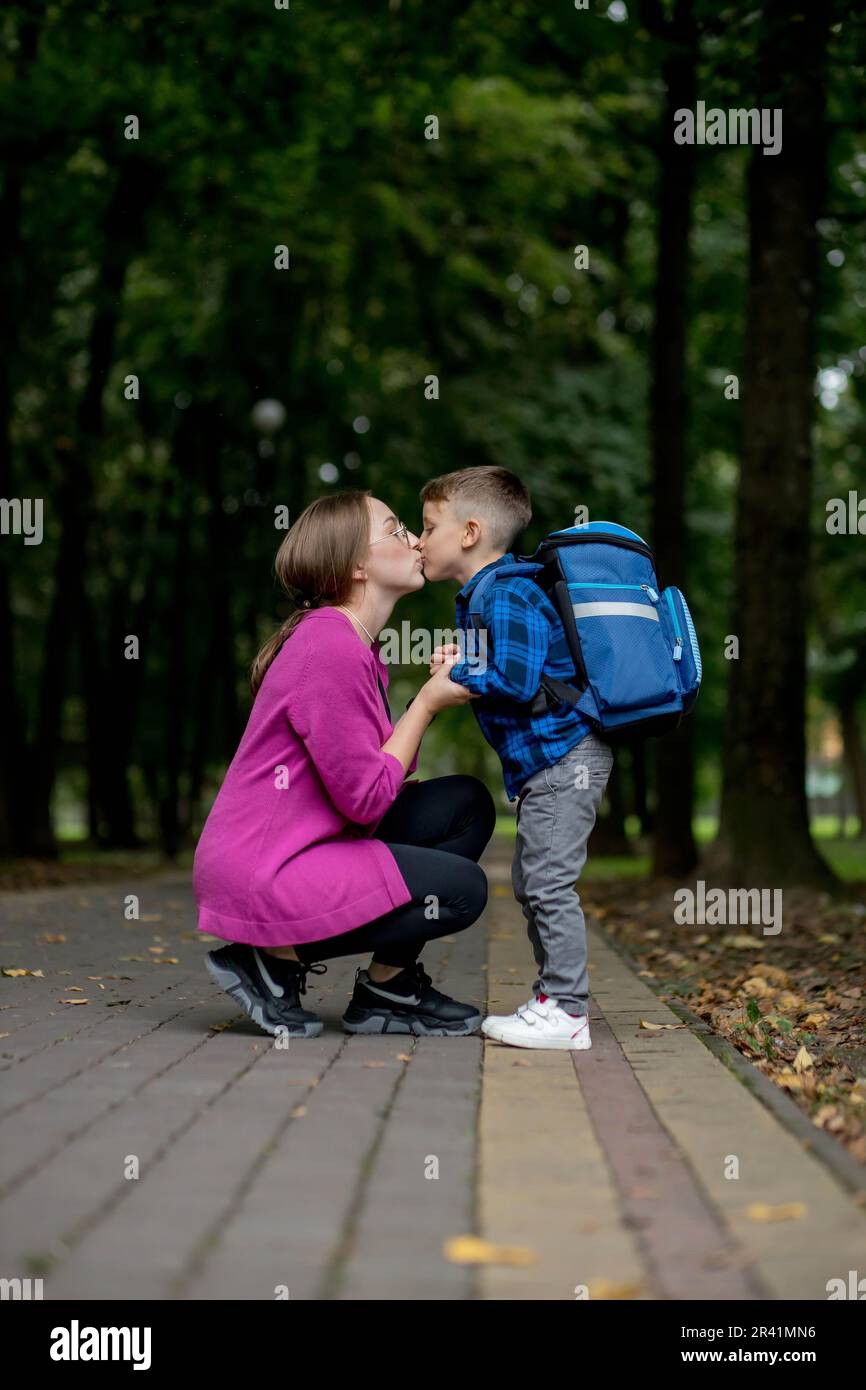 Young mother embraces her excited first class son on the way to school ...