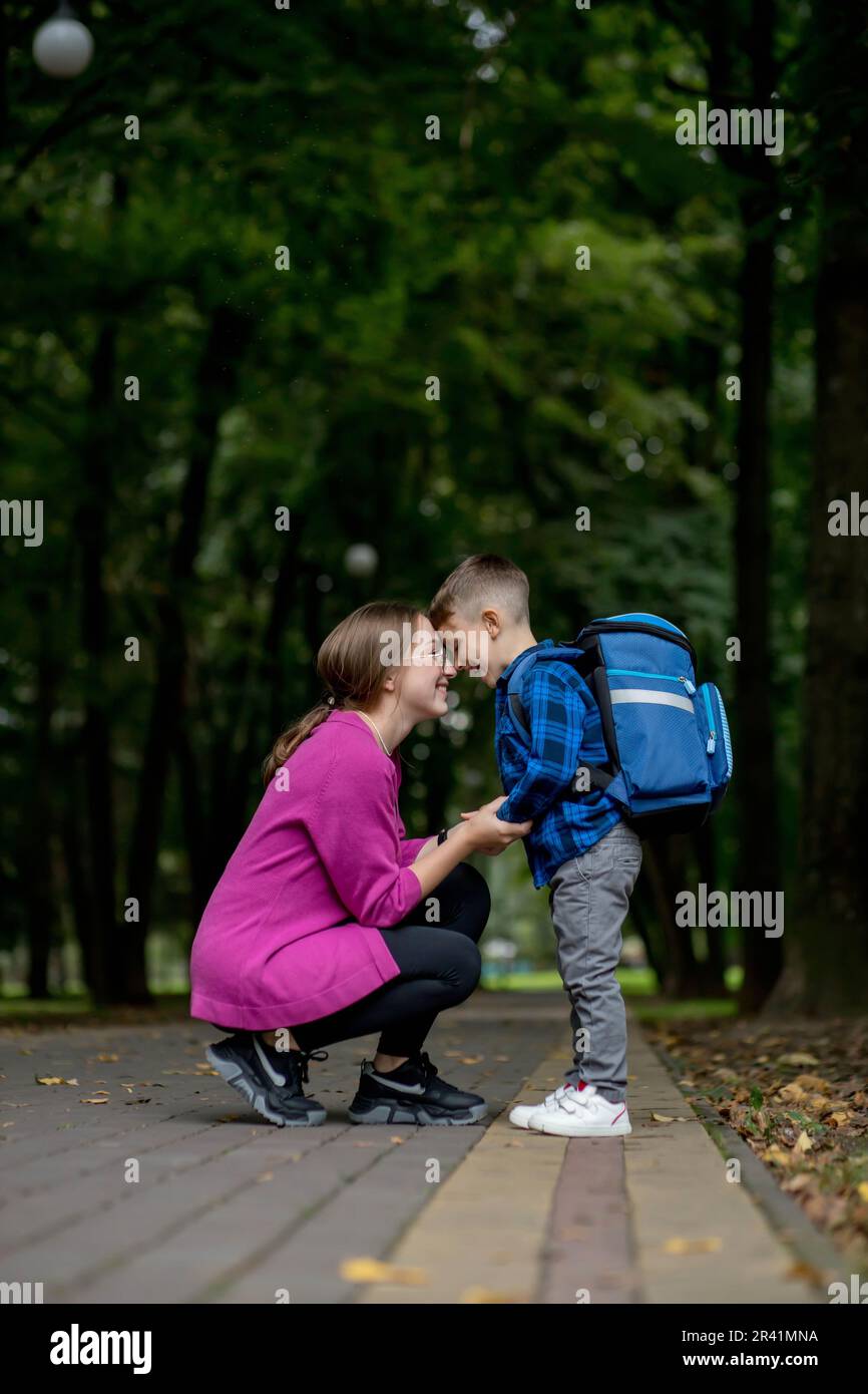 Young mother embraces her excited first class son on the way to school ...