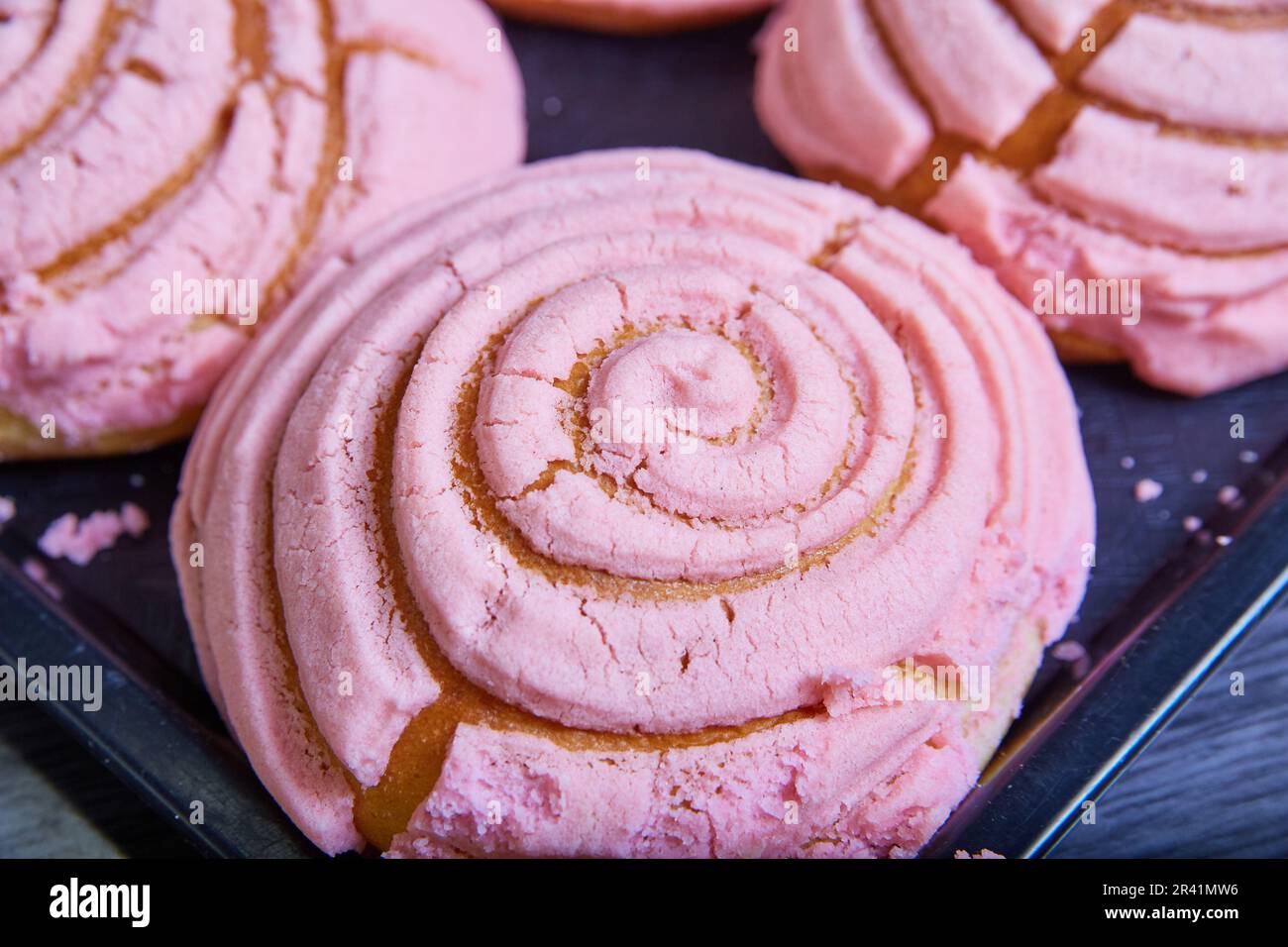 Single pink strawberry pastry baked good Mexican sweet bread conchas seashell swirl frosting ...