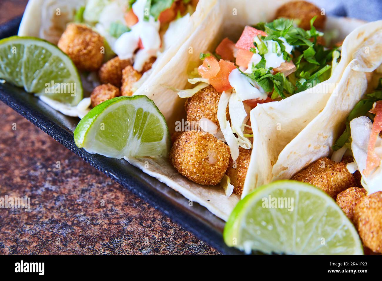 Lent fish tilapia tacos lime wedges sour cream cilantro tomato black ...