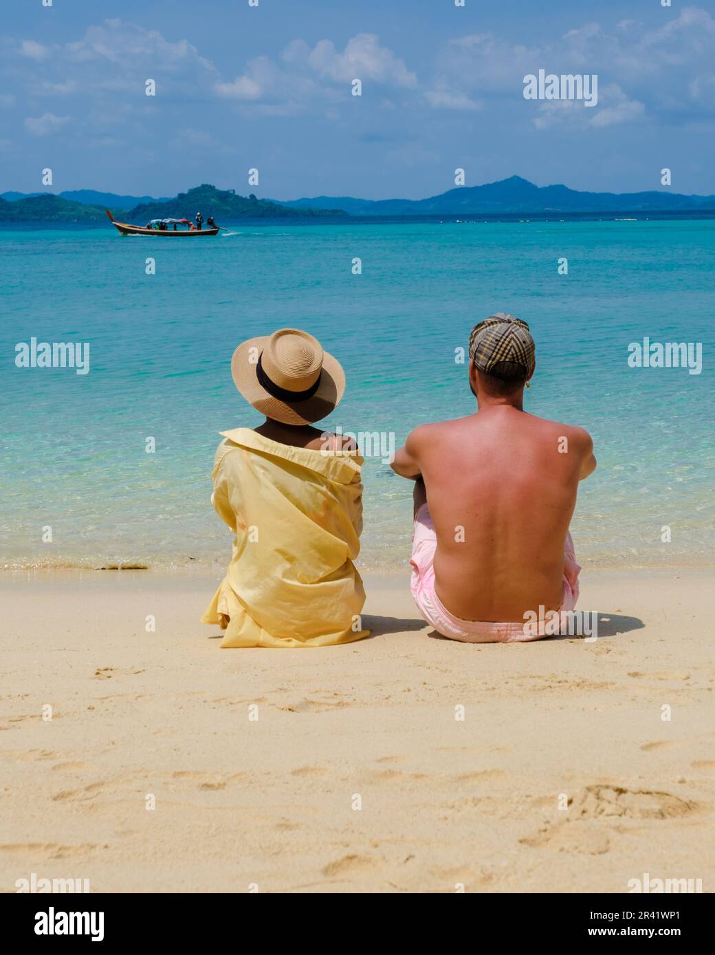 The backside of a couple of men and women sitting at the beach of Koh ...
