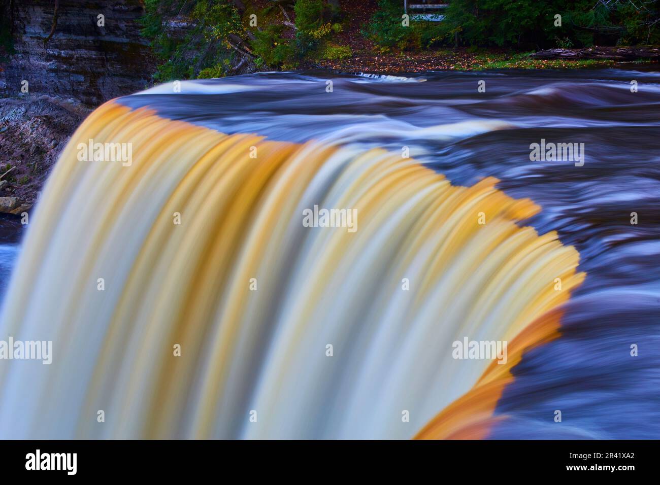 Smooth blue waters with white and golden brown waterfall at Tahquamenon ...