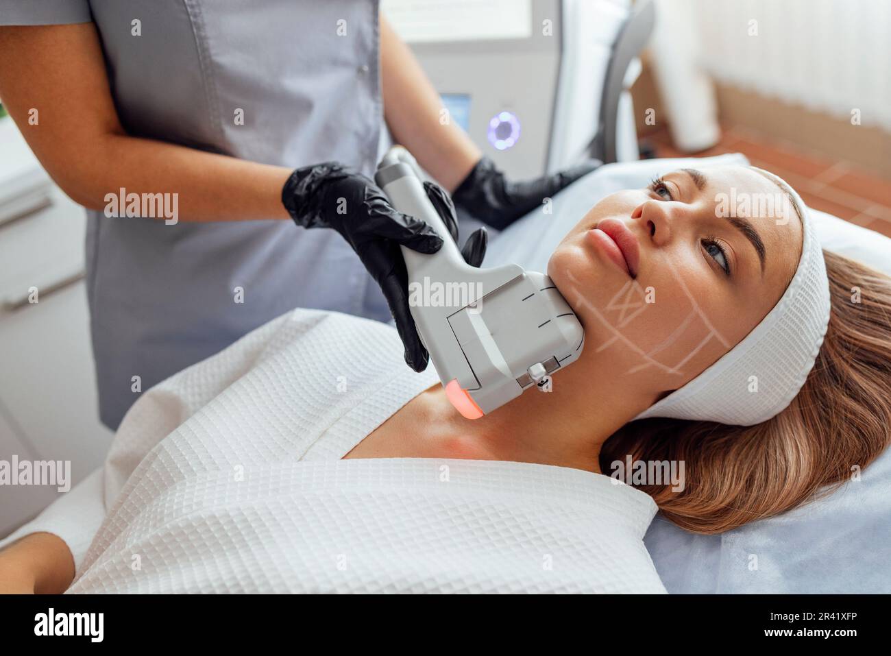 Portrait of relaxed young female client getting SMAS ultrasound face ...