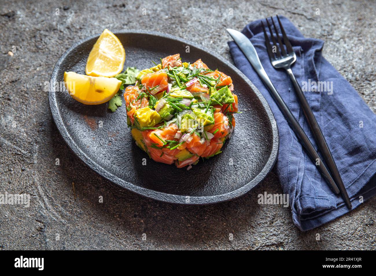 PERUVIAN NIKKEI FOOD. Salmon avocado ceviche on black plate, black ...