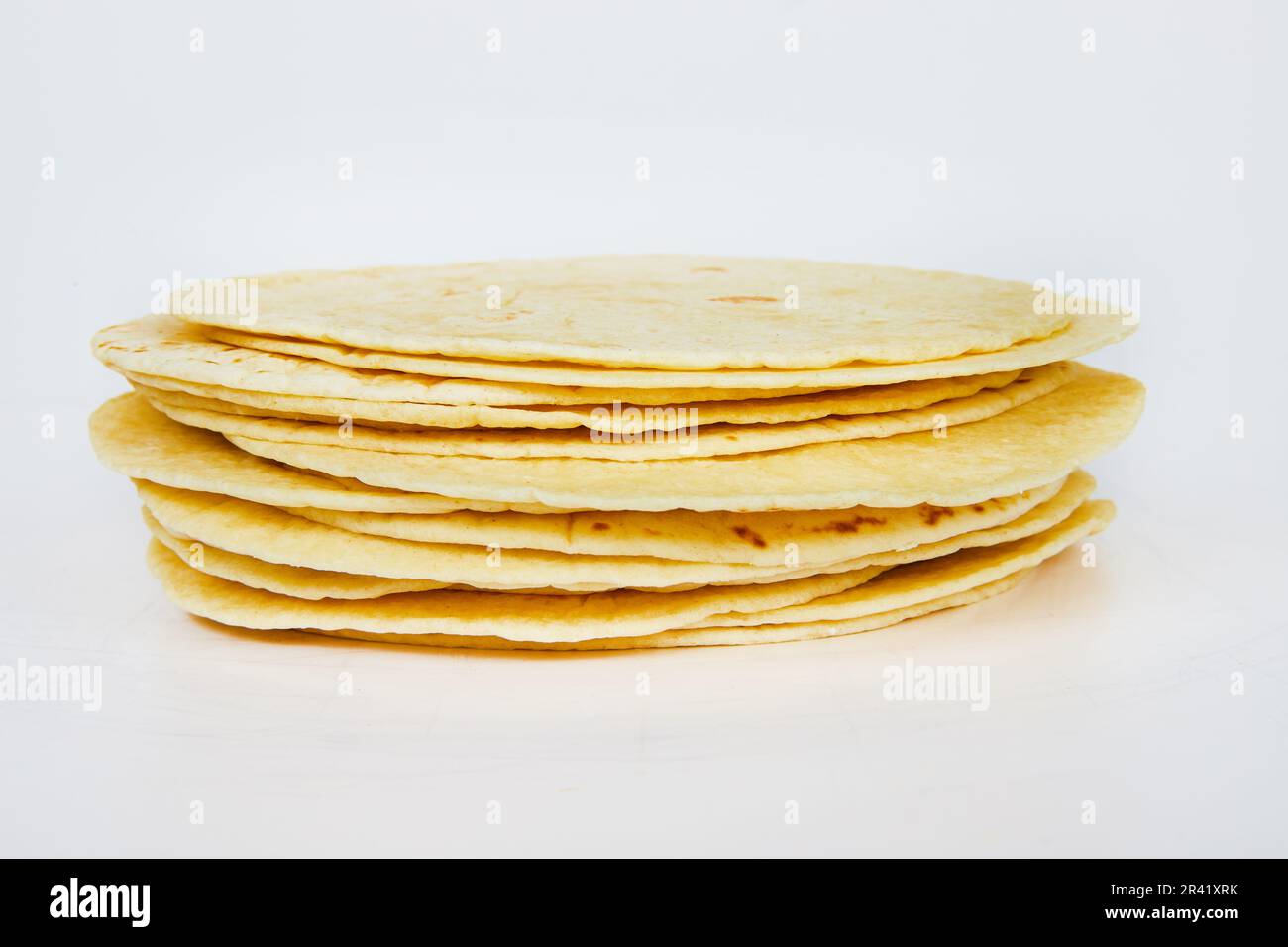Side view of a stack of 20 flour tortillas pre-grilled on white ...