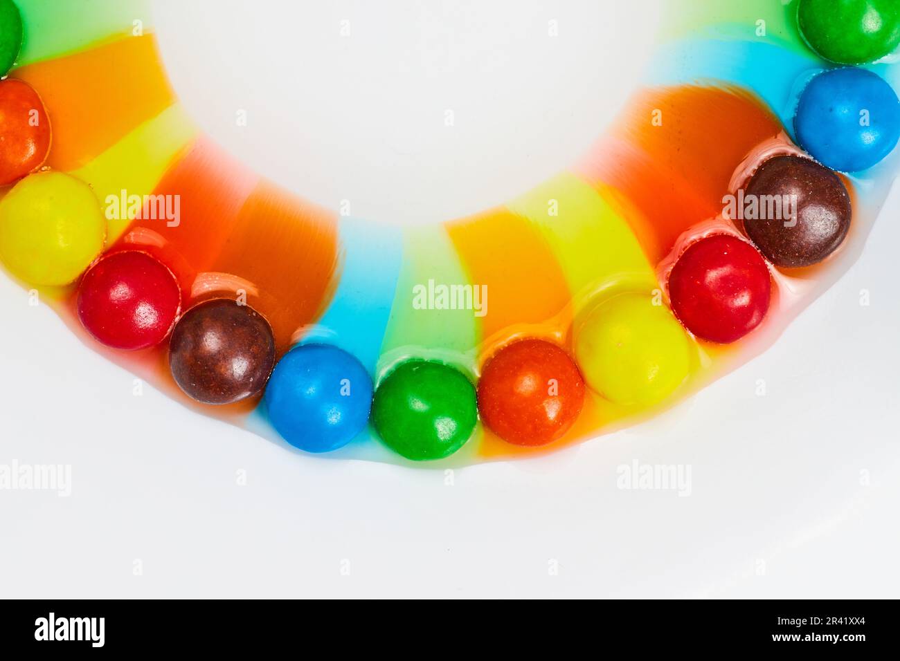 Smile of rainbow colors from skittles candy mixing with water on white ...