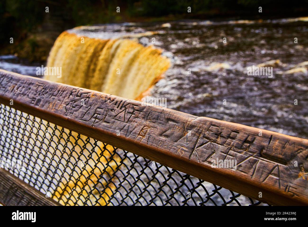 Chain wire link fence with old wood handrail with etched patterns and ...