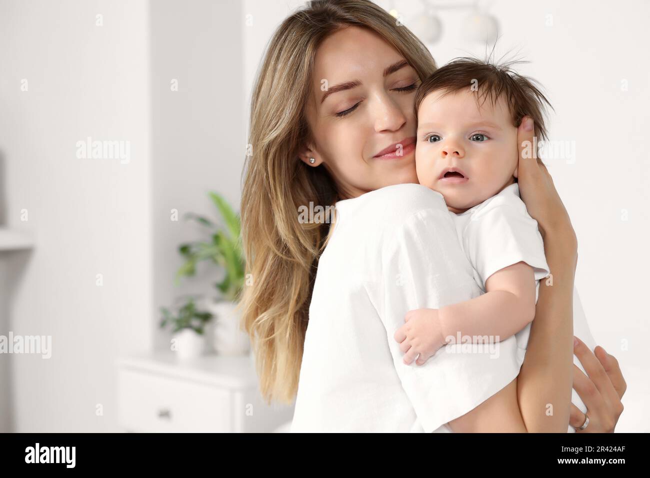 Mother hugging her cute little baby in room Stock Photo - Alamy