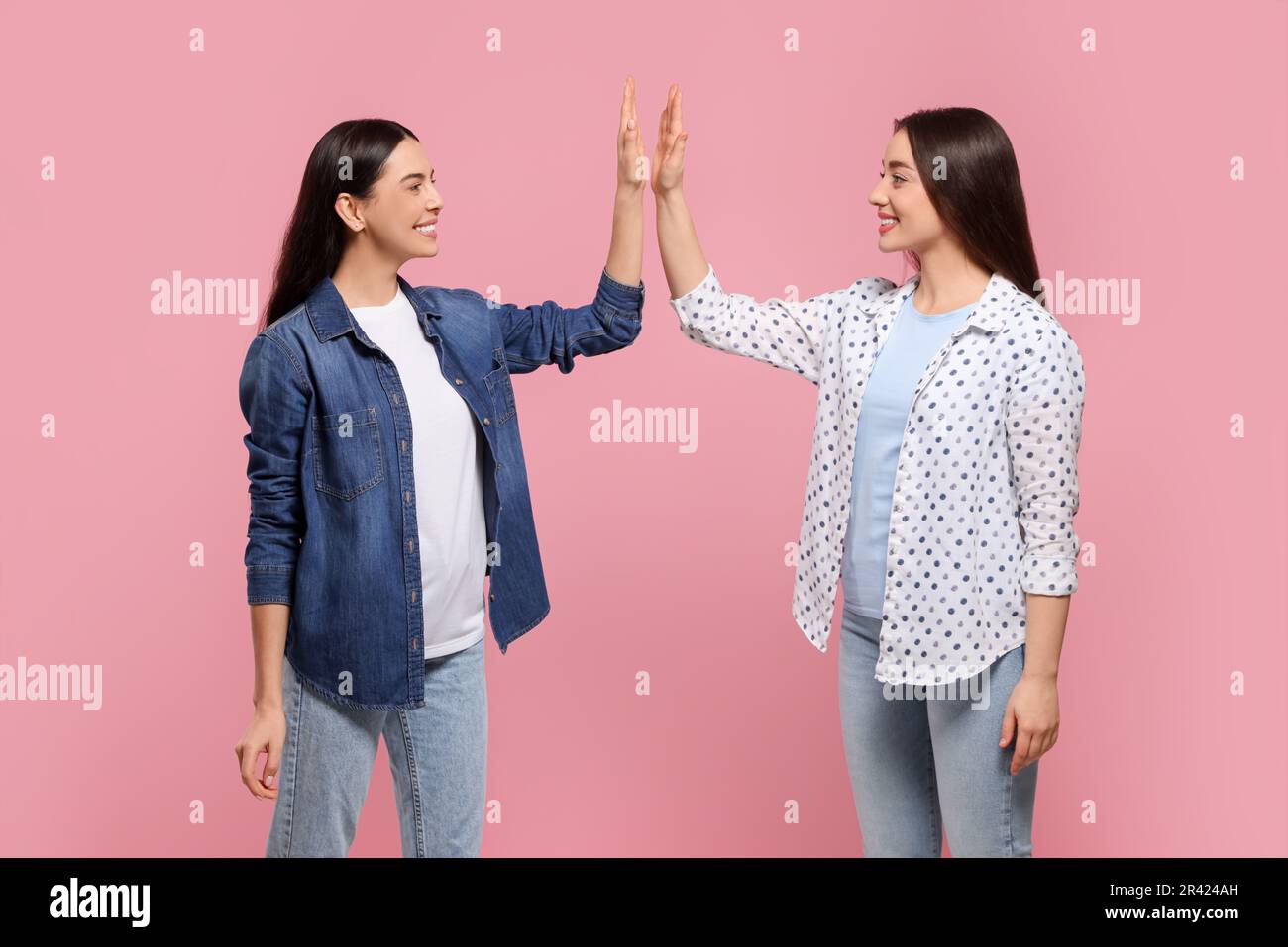 Women giving high five on pink background Stock Photo - Alamy