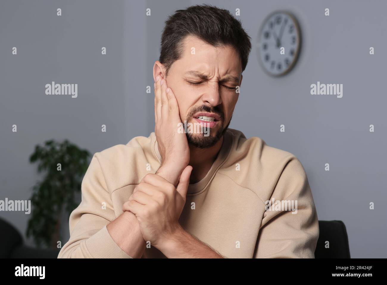 Man suffering from ear pain on in room Stock Photo - Alamy