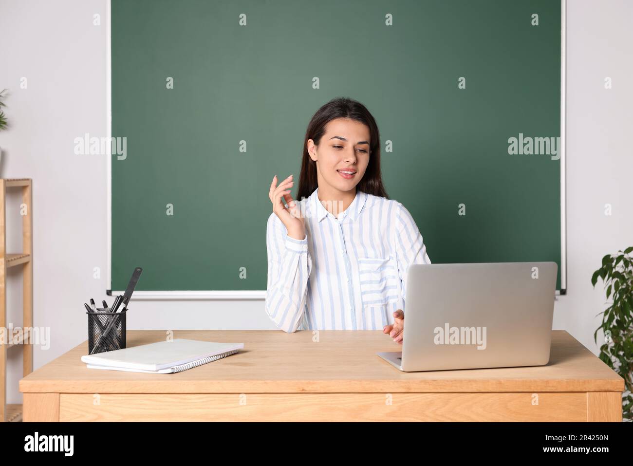 Young teacher giving lesson at table in classroom Stock Photo - Alamy