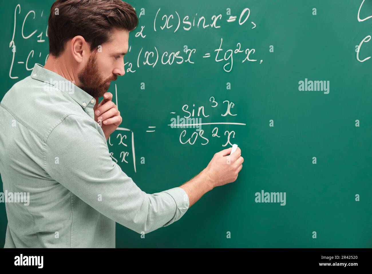 Mature teacher explaining mathematics at chalkboard in classroom Stock ...