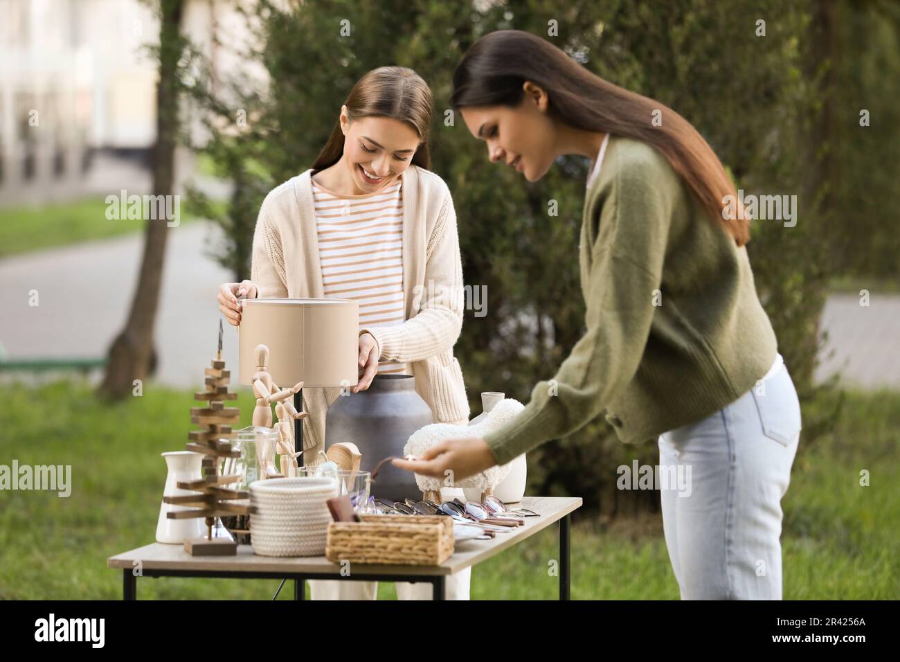 Women shopping at table in yard. Garage sale Stock Photo - Alamy