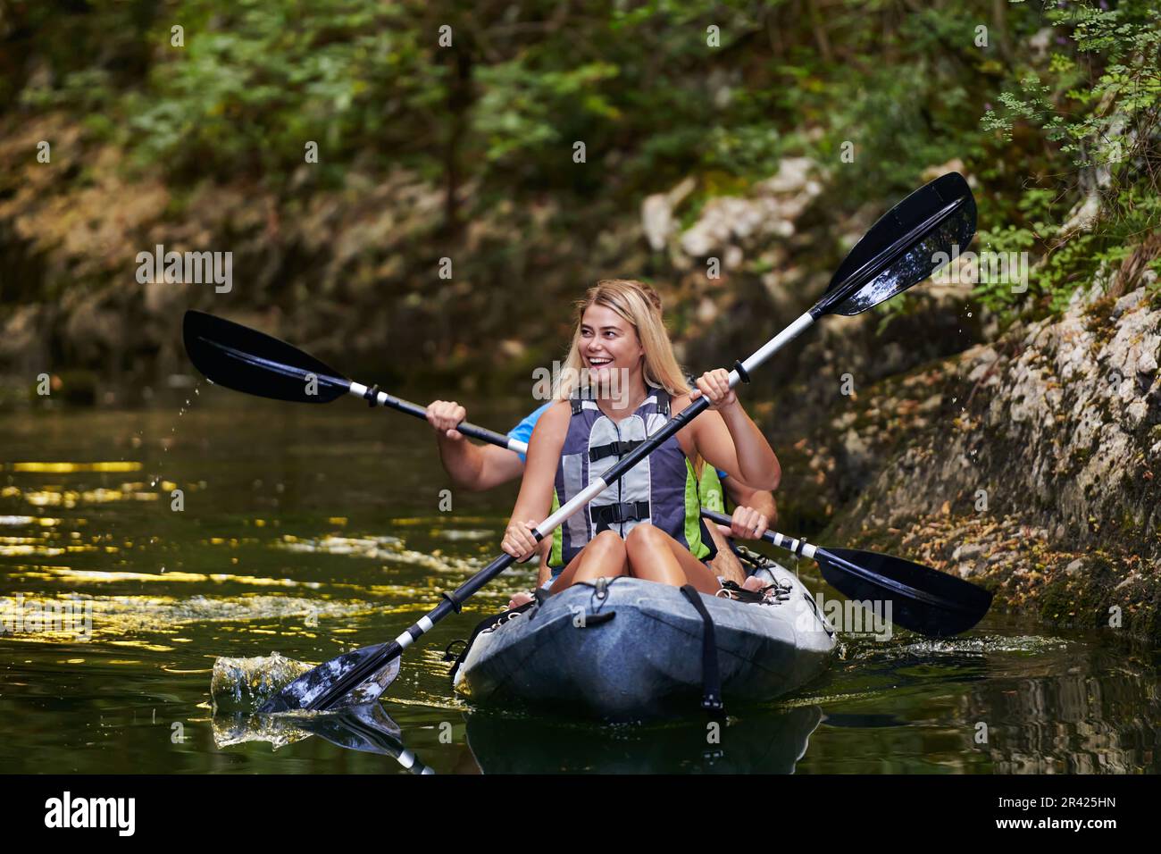 A young couple enjoying an idyllic kayak ride in the middle of a ...