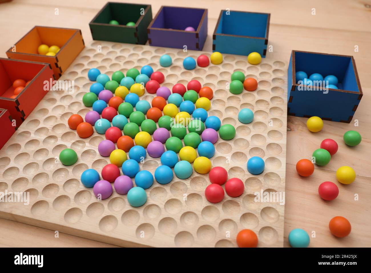 Wooden sorting board and boxes with colorful balls on table, closeup ...