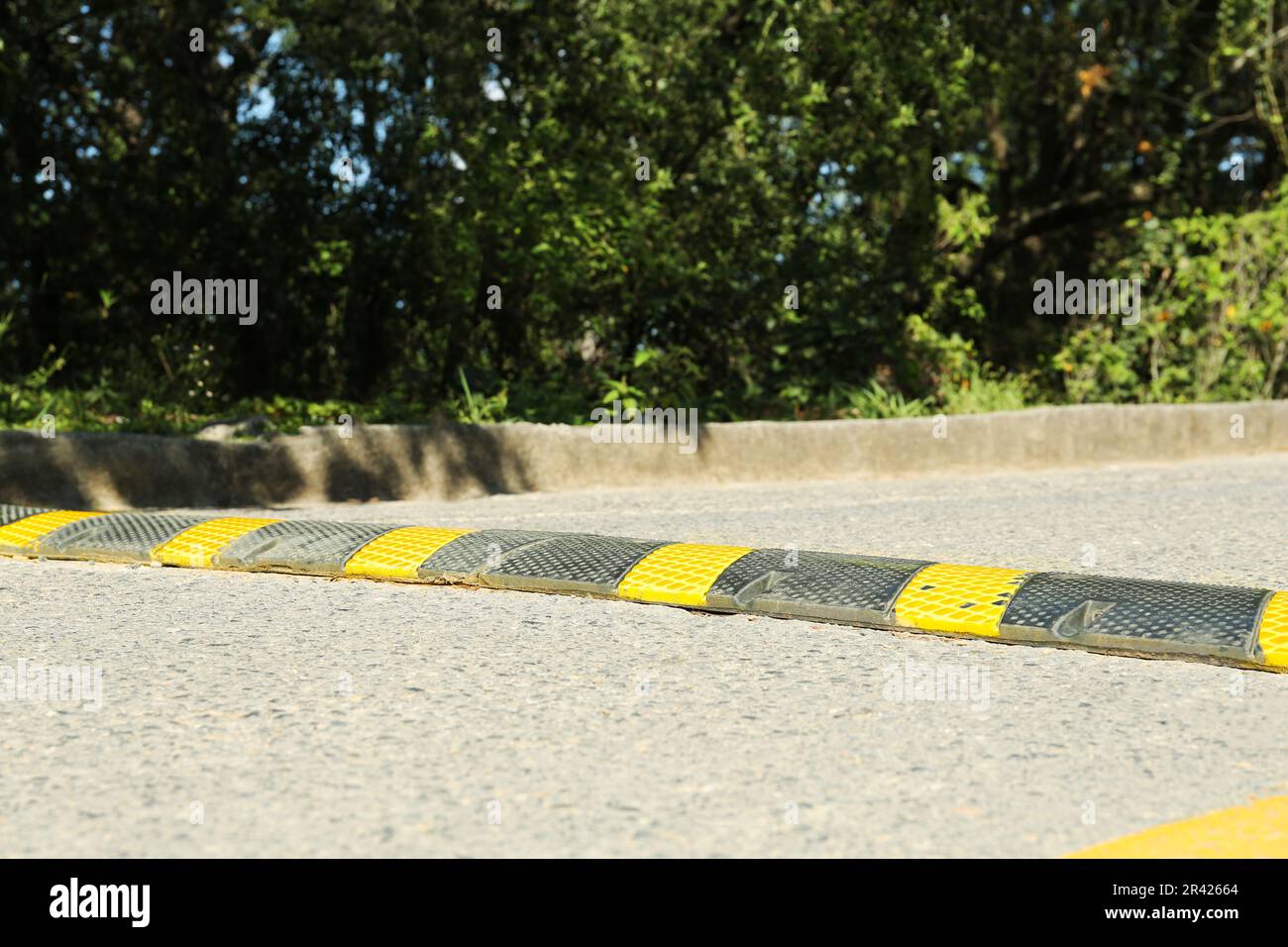 Speed bump on asphalt road near trees outdoors Stock Photo - Alamy