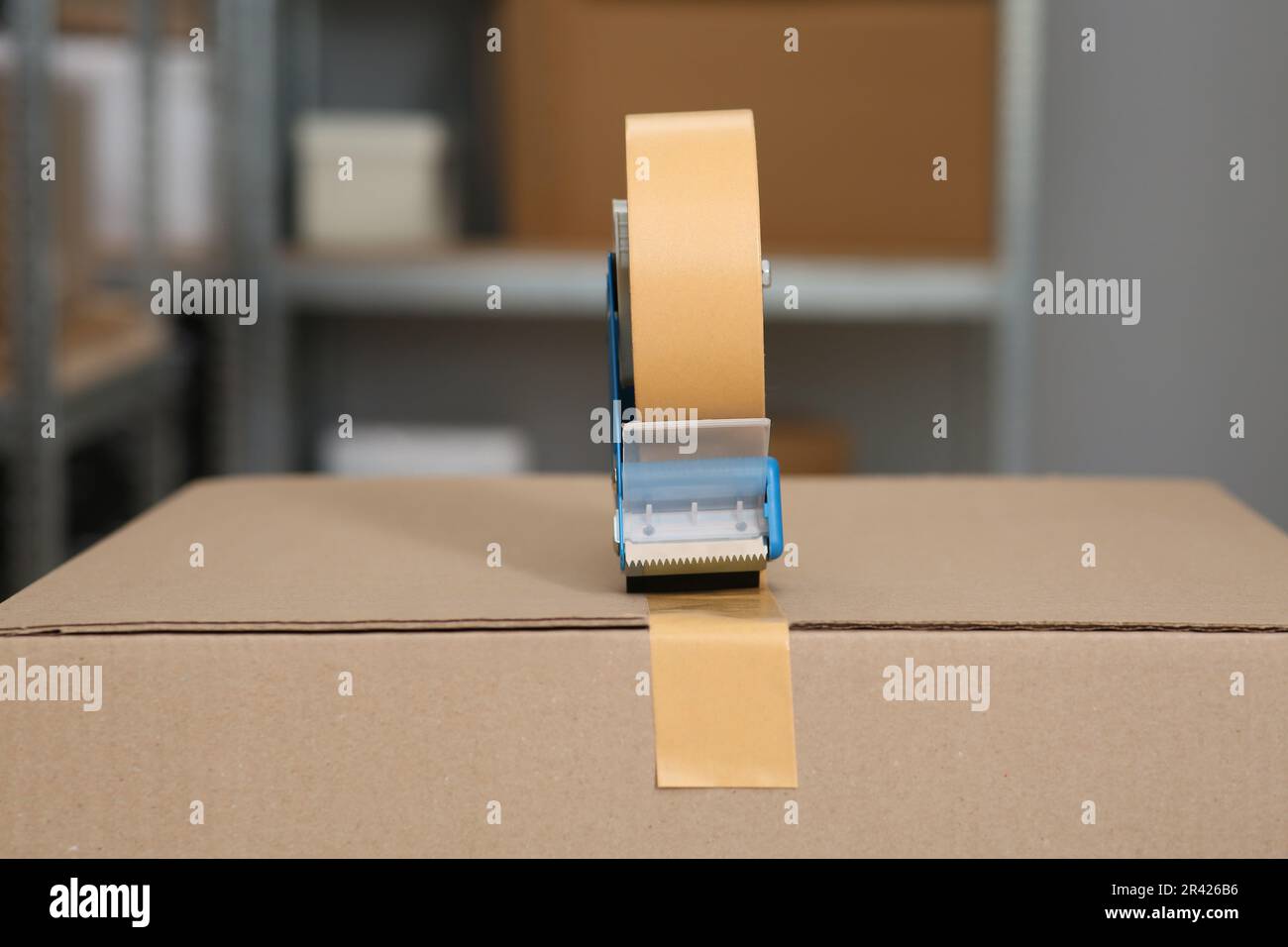 Taping cardboard box with adhesive tape dispenser indoors Stock Photo ...