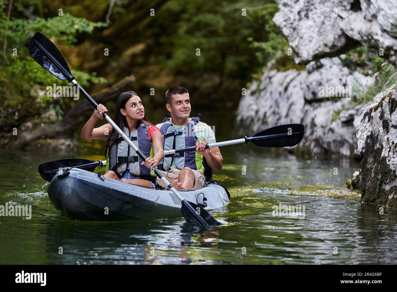 A young couple enjoying an idyllic kayak ride in the middle of a ...