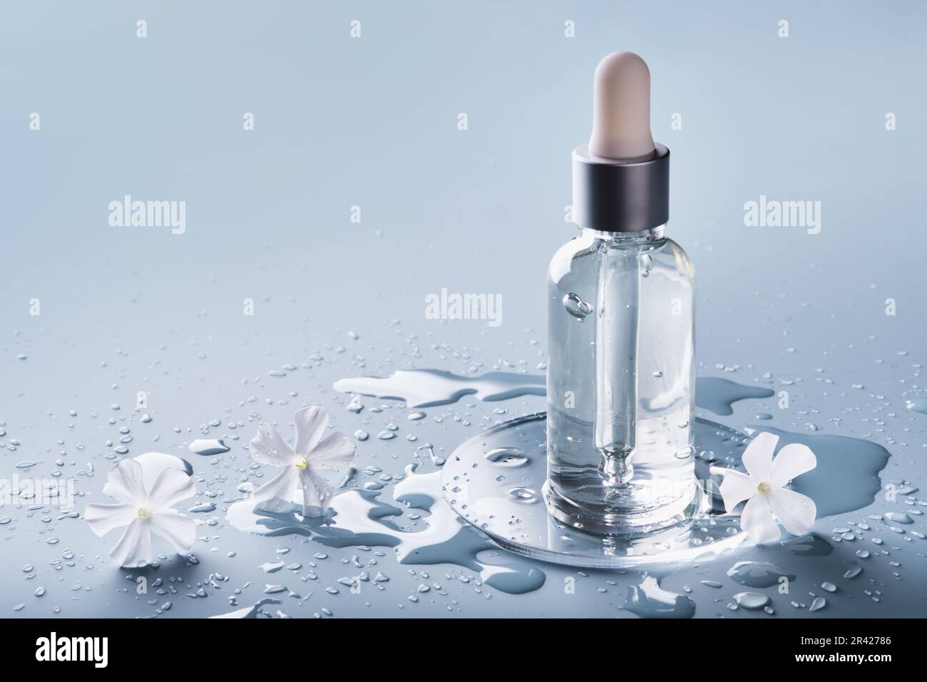 Cosmetic product bottle and glass slide on blue splash background ...