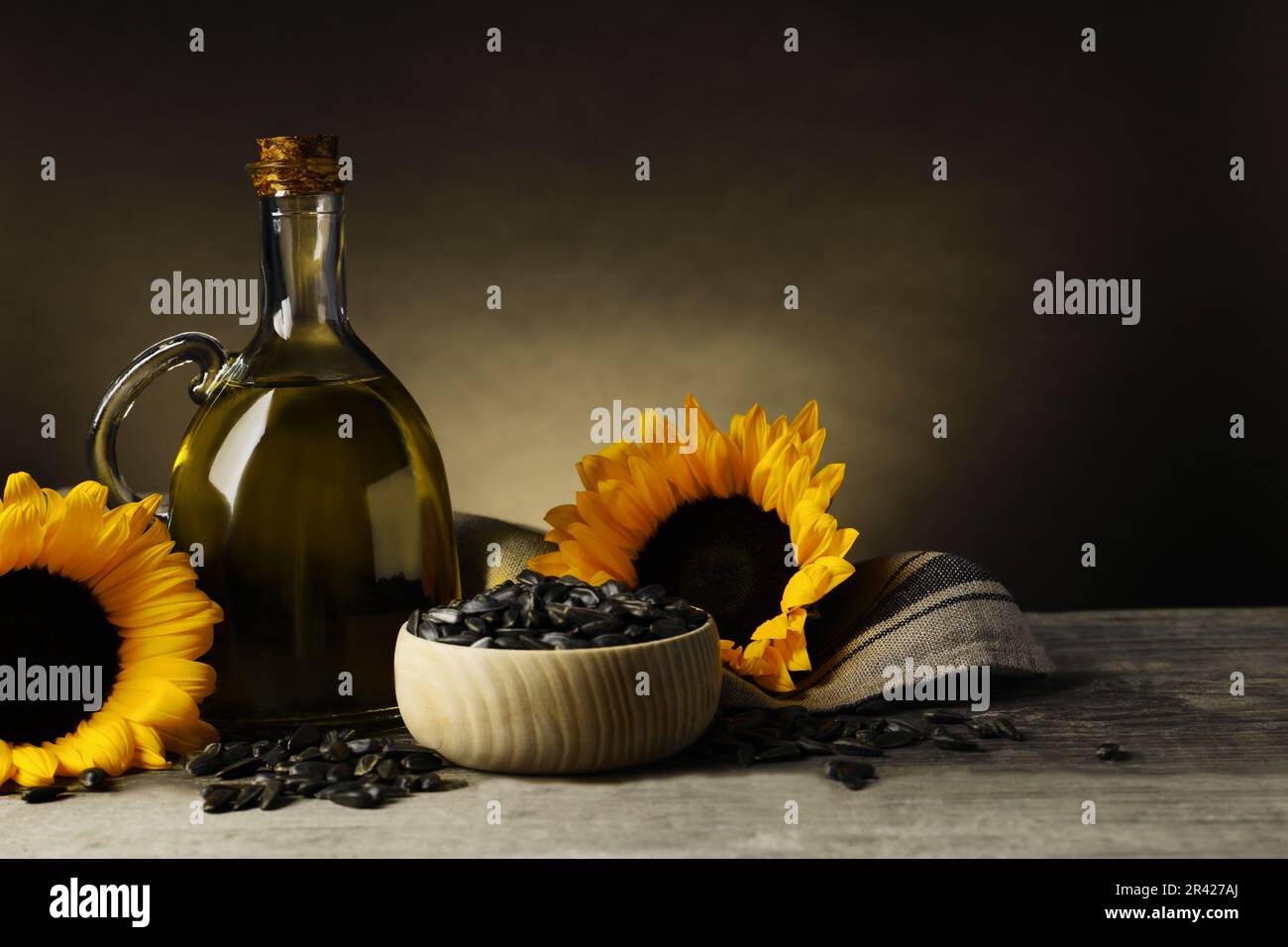 Sunflower cooking oil, seeds and yellow flowers on light grey table ...